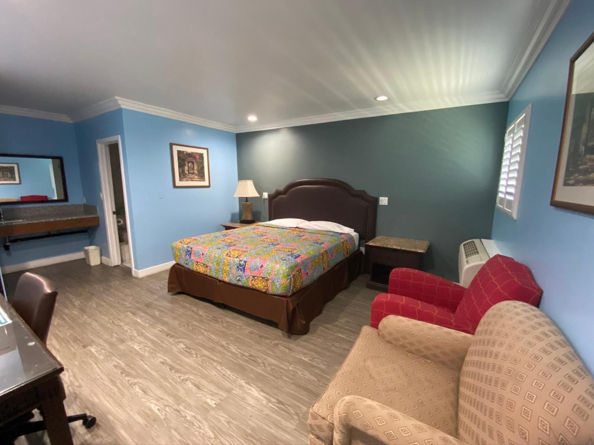 Quarto com cama, escrivaninha, cadeira e sofá.
