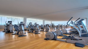 Uma academia ampla com diversos equipamentos de cardio e pesos livres.