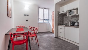 Cozinha compacta com armários brancos, micro-ondas, cafeteira e fogão a gás.