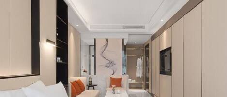 Quarto de hotel moderno com uma cama grande, um sofá, uma mesa pequena e um closet espaçoso.