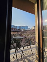 Uma varanda com vista para a paisagem urbana, com guarda-corpo de metal e uma mesa com cadeiras.