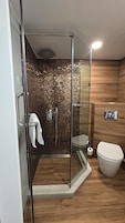 Um banheiro moderno com chuveiro envidraçado, piso de madeira e vaso sanitário branco.