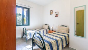 Quarto com duas camas, uma janela e uma porta.
