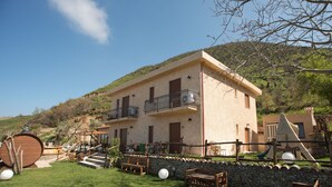 Um edifício de dois andares com varanda, parede de pedra e área de estar ao ar livre.