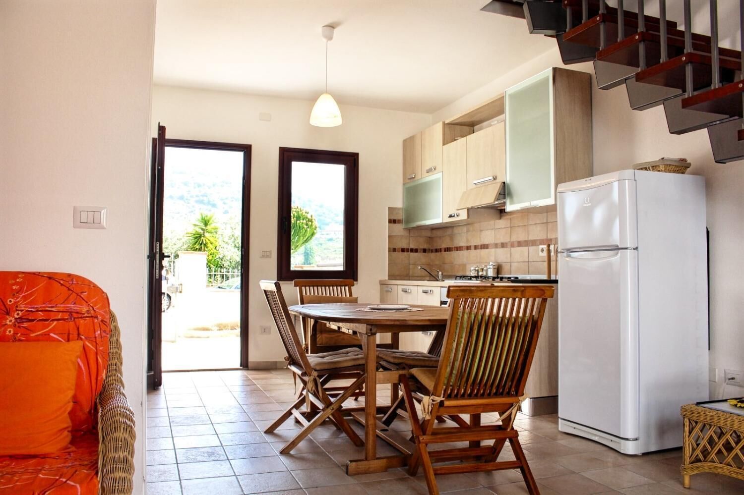 Uma cozinha compacta com mesa e cadeiras, geladeira e escada que leva a um andar superior.