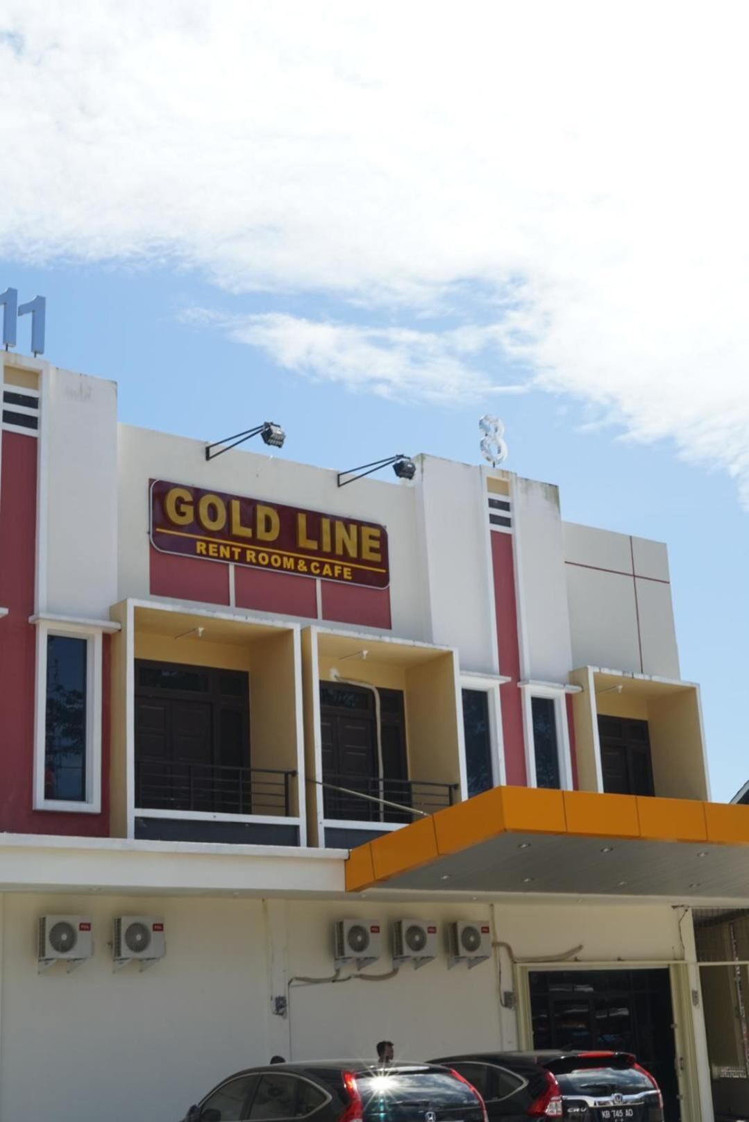 Um edifício com uma placa que diz 'GOLD LINE RENT ROOM & CAFE'.