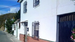 Uma casa de dois andares com fachada branca, seção inferior com telhas vermelhas e porta de garagem preta.