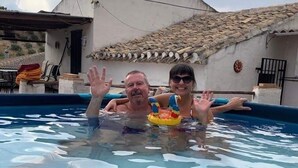 Piscina com cobertura em azulejo e um edifício ao fundo.