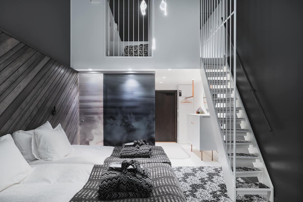 Quarto moderno com cama, escada e vista para a paisagem urbana.