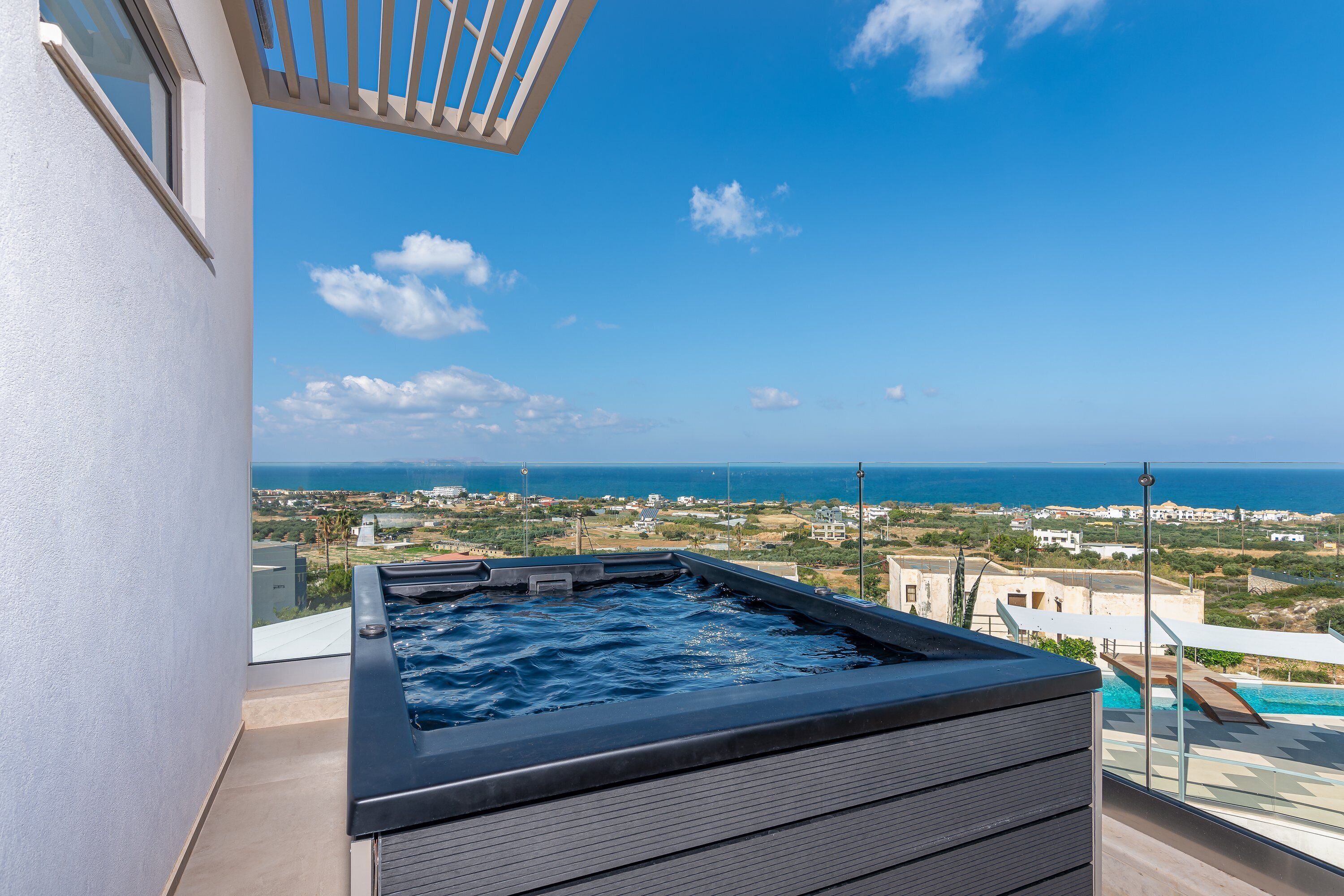 Uma banheira de hidromassagem em uma varanda com vista para o mar e edifícios.