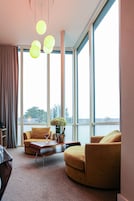 Uma sala de estar moderna com janelas amplas, um sofá, uma mesa de centro e um lustre.