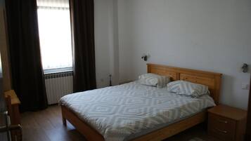 Um quarto com cama de madeira, mesa de cabeceira e janela com cortinas.