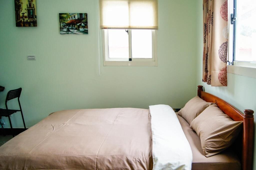 Quarto com uma cama de solteiro, uma janela com cortinas e duas imagens penduradas na parede.