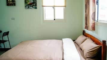 Quarto com uma cama de solteiro, uma janela com cortinas e duas imagens penduradas na parede.