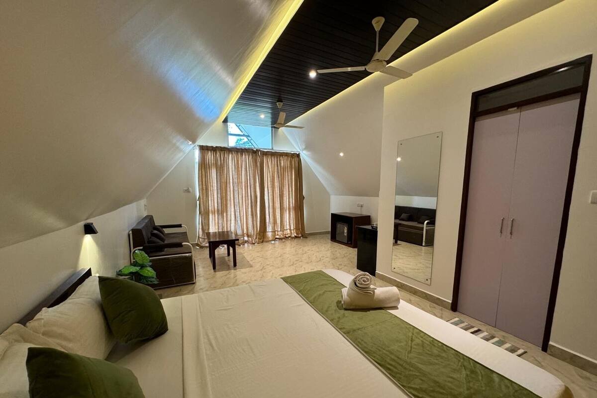 Um quarto moderno e bem iluminado, com uma cama grande, uma escrivaninha, uma cadeira, um espelho e um guarda-roupa.