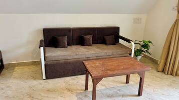 Uma sala de estar com um sofá, uma mesa de centro de madeira e um vaso de planta.