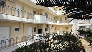 Um edifício com várias andares, varandas, aparelhos de ar condicionado e um pátio central com plantas.