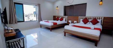 Quarto de hotel com duas camas, uma escrivaninha, ventoinha no teto, ar condicionado e janela com cortinas.