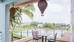 Varanda com mesa e cadeiras, vista para um rio e vegetação.