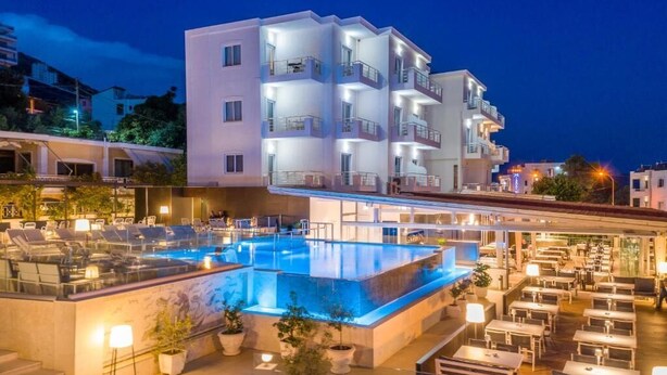 Um hotel com piscina no terraço, área de estar ao ar livre e várias varandas.