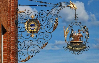 Placa de hotel com design tradicional, exibindo o logotipo de uma cerveja e a representação de um homem com vestimentas históricas.