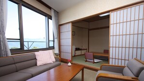 Quarto em estilo japonês tradicional com tatames, uma mesa de madeira baixa, um sofá e painéis deslizantes shoji.