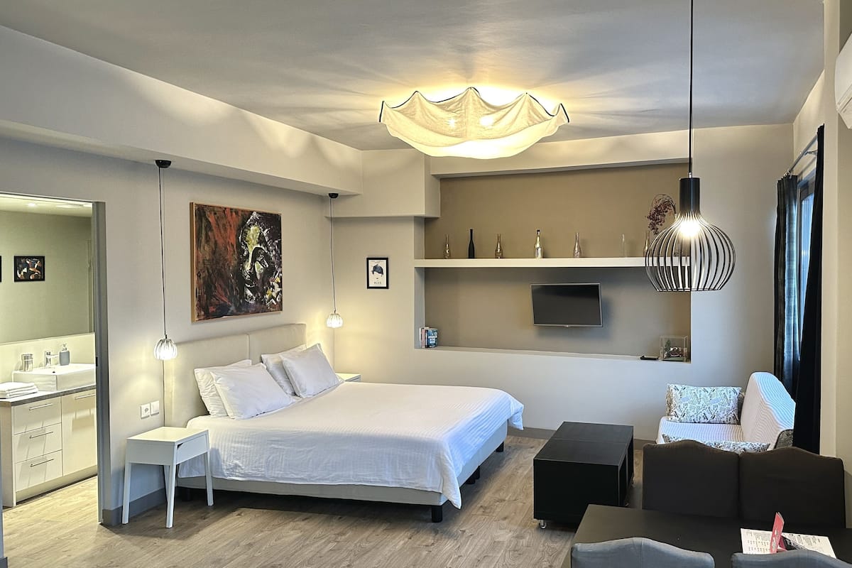 Quarto moderno com uma cama grande, mesas de cabeceira, televisão e obras de arte nas paredes.