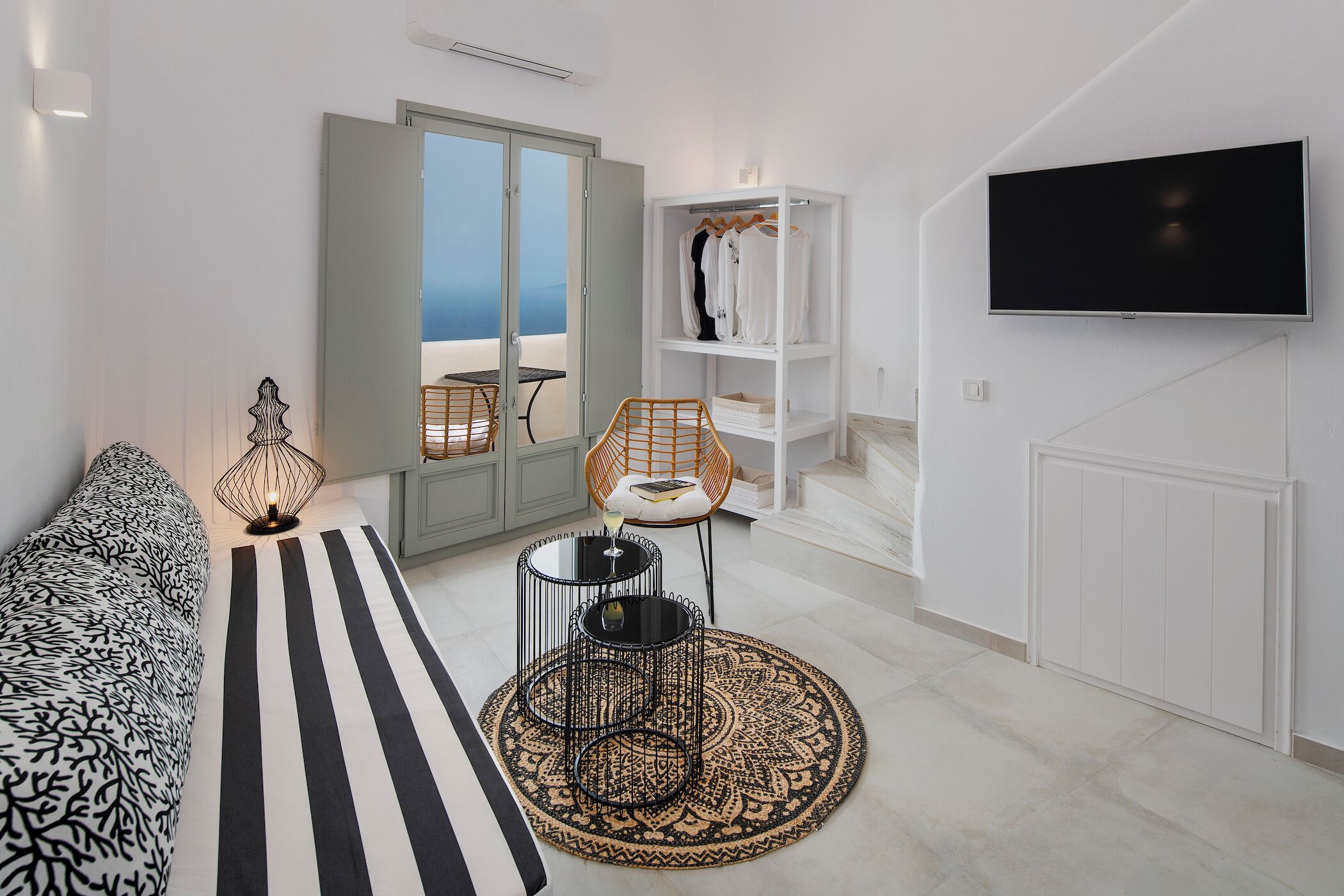 Uma sala de estar moderna com um sofá, uma mesa redonda, uma televisão e um guarda-roupa.
