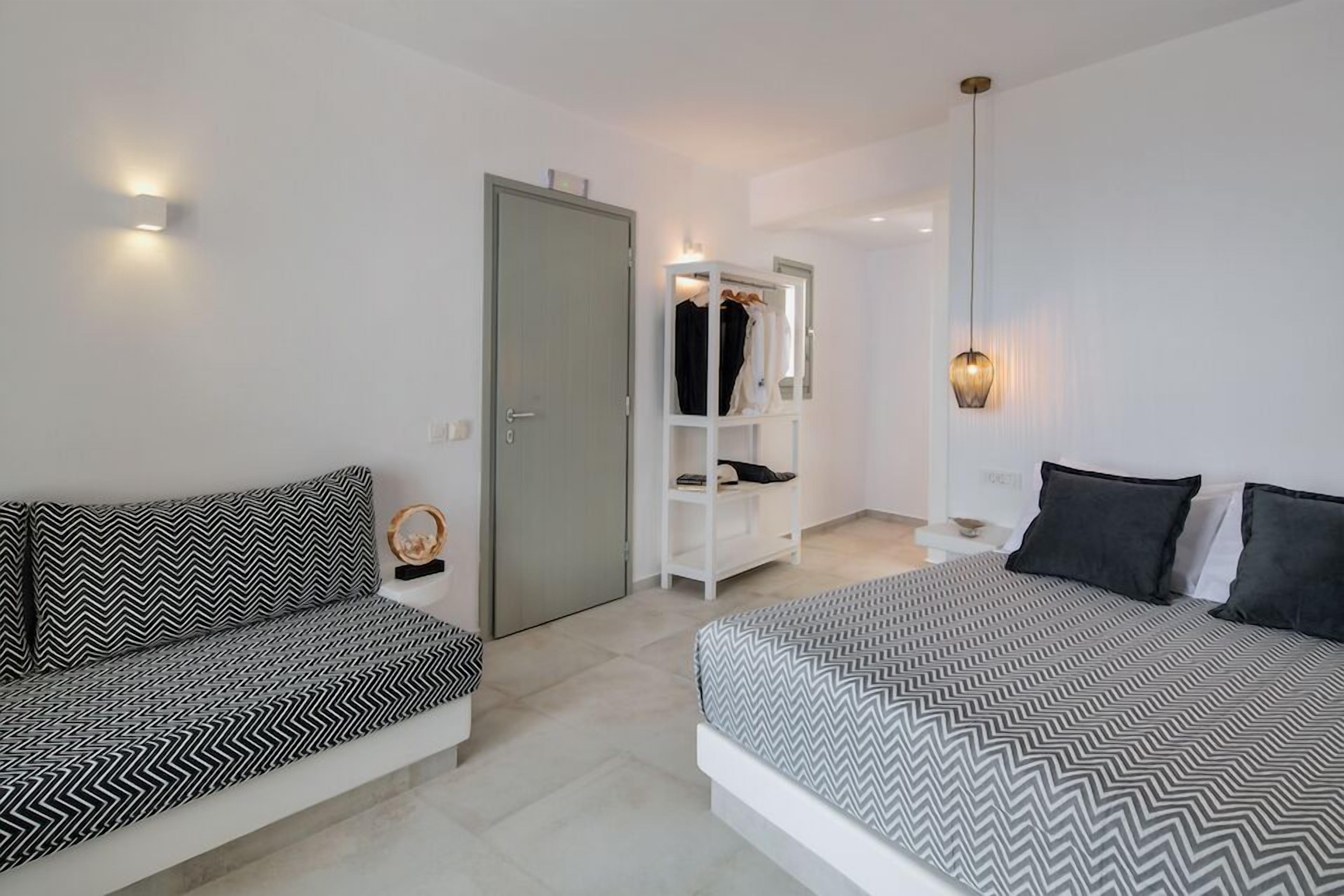 Um quarto moderno com cama, sofá, guarda-roupa e espelho.