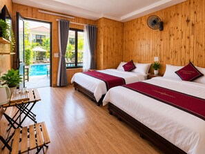 Quarto de hotel com duas camas, piso de madeira, vista para piscina e ventoinha na parede.