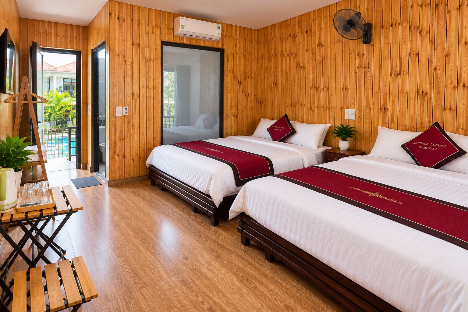 Quarto de hotel com duas camas, paredes e piso de madeira, uma escrivaninha com cadeira e vista para o exterior.