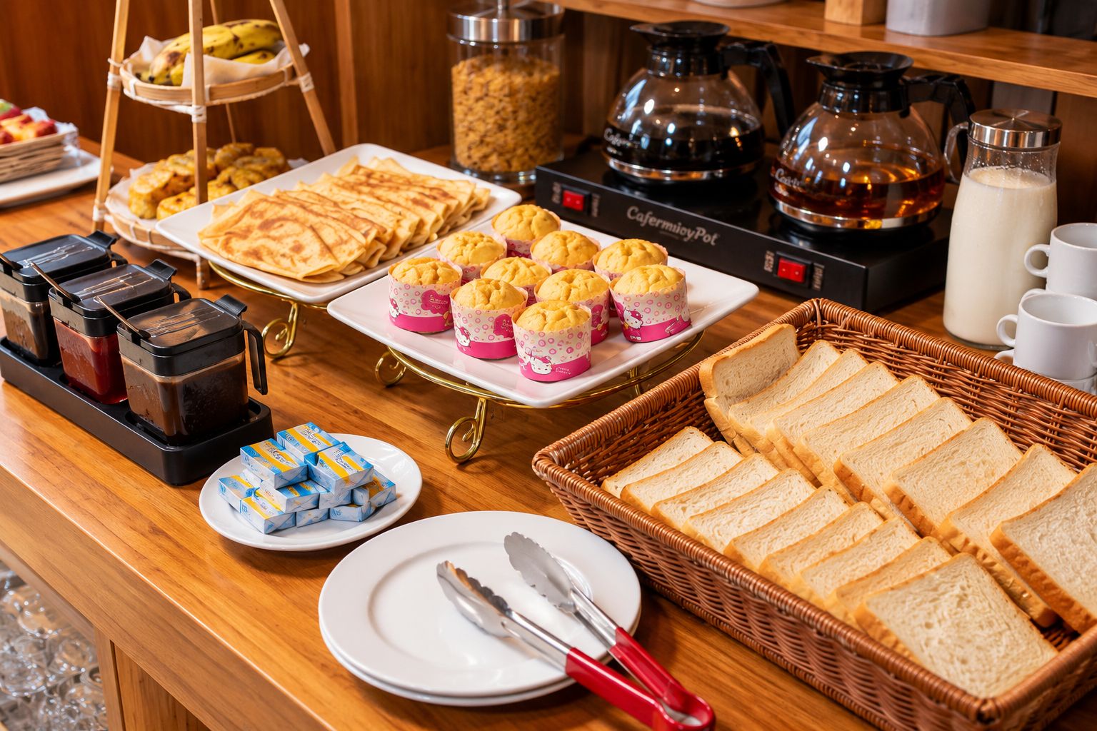 Disposição de buffet com diversos itens de comida, incluindo doces, sanduíches e bebidas.