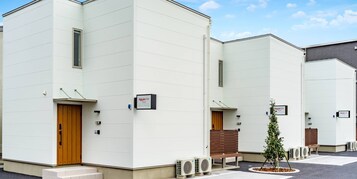 Um edifício moderno com várias unidades, cada uma com porta de madeira e placa indicando "Rakuten Stay".