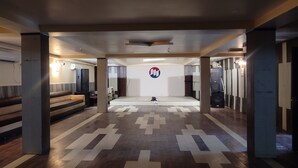 Um espaço interno amplo com piso estampado, assentos à esquerda e um palco com um logotipo no centro.