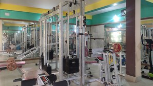 Academia com diversos equipamentos de ginástica, incluindo aparelhos de musculação e pesos livres.