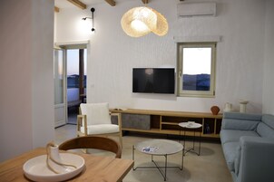 Sala moderna com televisão de tela plana, sofá, mesa de jantar e uma grande janela com vista.