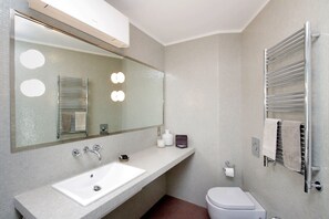 Casa de banho moderna com uma pia branca, espelho e porta-toalhas.