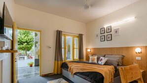 Quarto com cama, cabeceira de madeira, mesa de cabeceira, abajur e janela com cortinas.