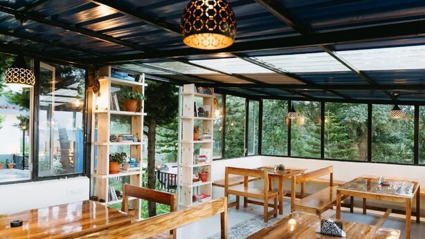 Um interior moderno com móveis de madeira, mesas de vidro e uma grande estante de livros.