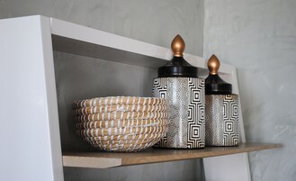 Uma prateleira com uma cesta trançada e dois recipientes estampados.