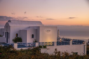 Um edifício branco com guarda-corpo de varanda azul e um letreiro que diz 'PERGERI APARTMENTS'.