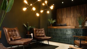 Uma área de recepção com poltronas de couro, um balcão de madeira e uma luminária moderna.