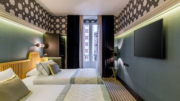 Quarto de hotel com duas camas, televisão e vista para o exterior.