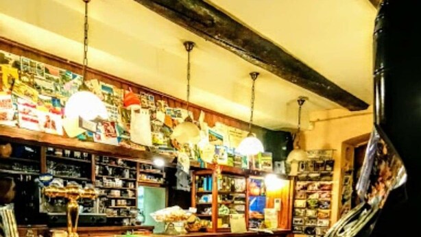 Uma área de bar com paredes de tijolo, banquetas de madeira e luminárias penduradas.
