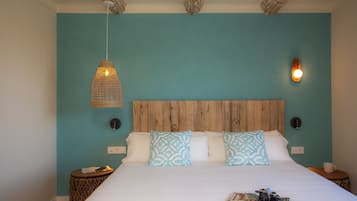 Cama bem arrumada com almofadas estampadas, luminária pendente e luminária na parede.