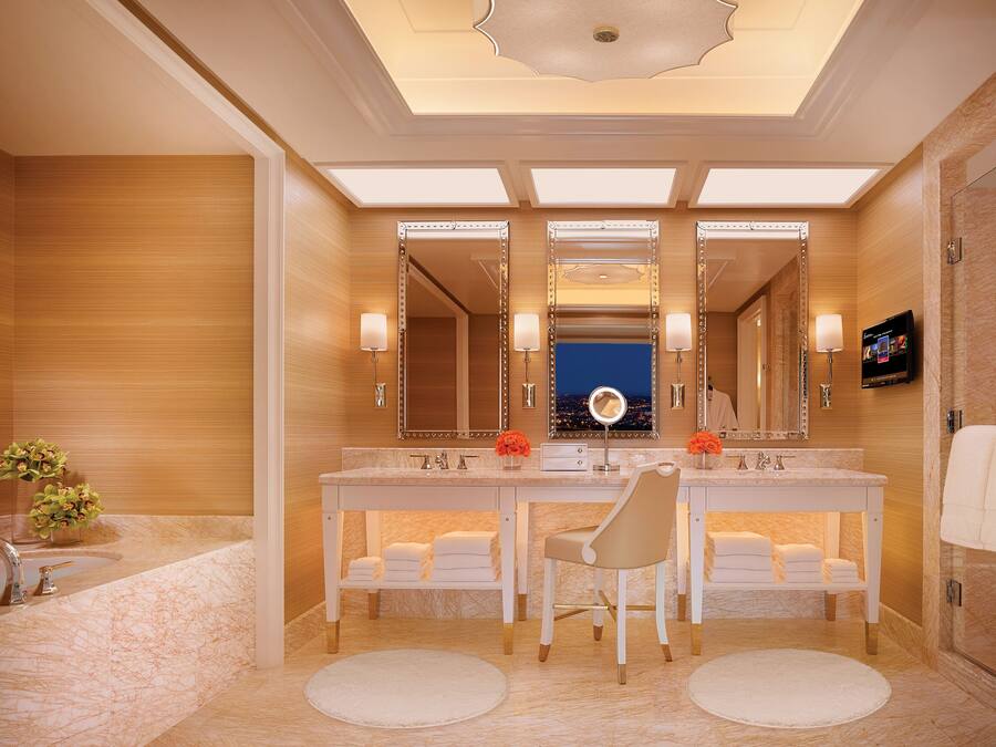 Um banheiro luxuoso com pia dupla, um espelho grande e um espaço para sentar.