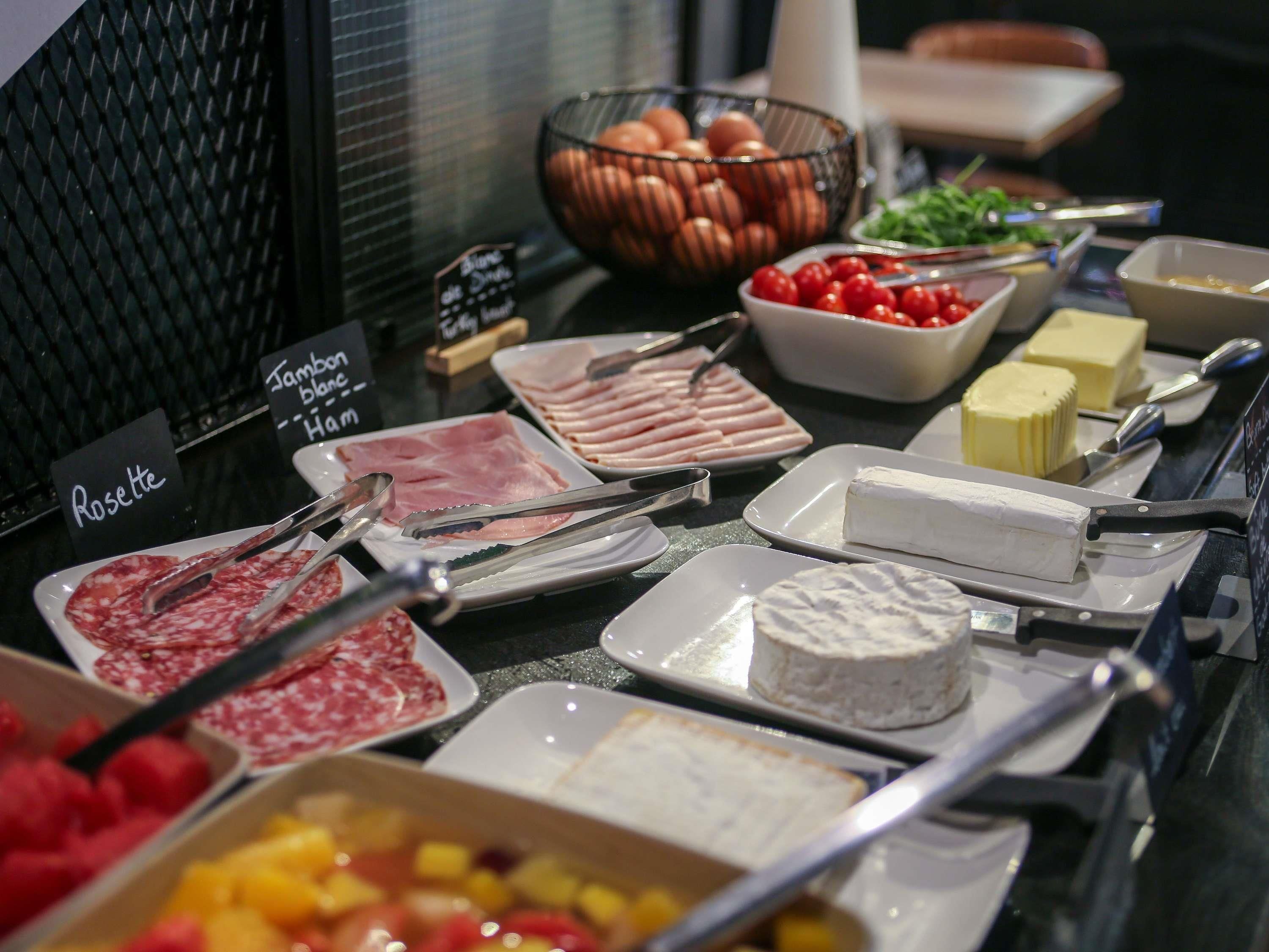 Buffet com diversas opções de comida, incluindo carnes, queijos e frutas.