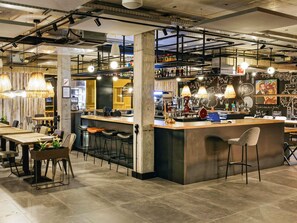 Uma área de bar moderna com ilha central, banquetas e luminárias pendentes.