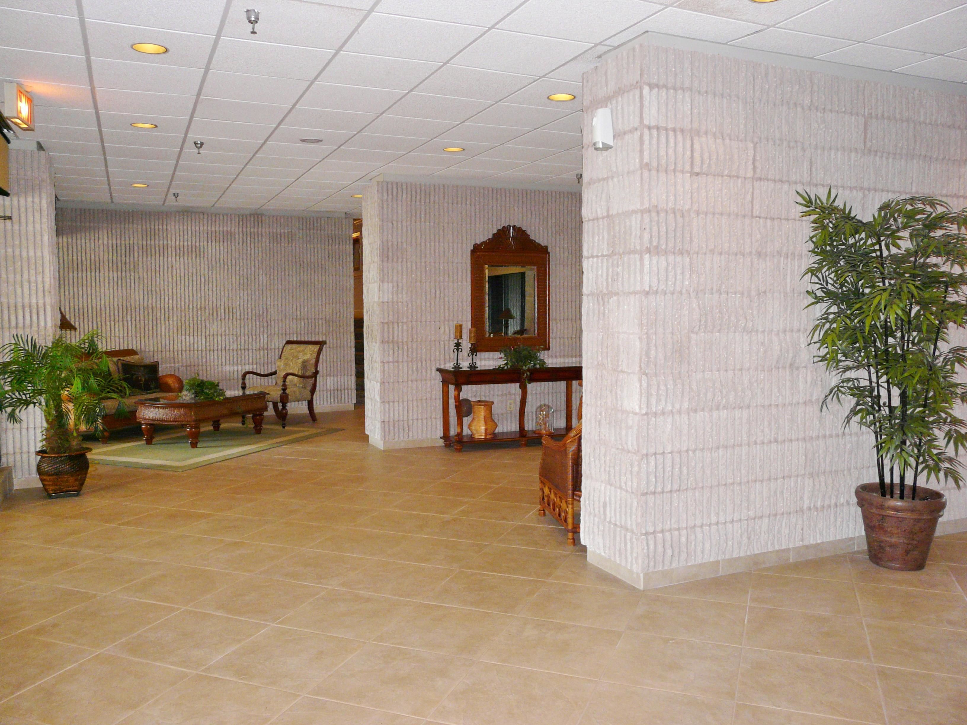 Um lobby amplo com teto alto, piso em azulejo e área de estar com sofá e poltronas.