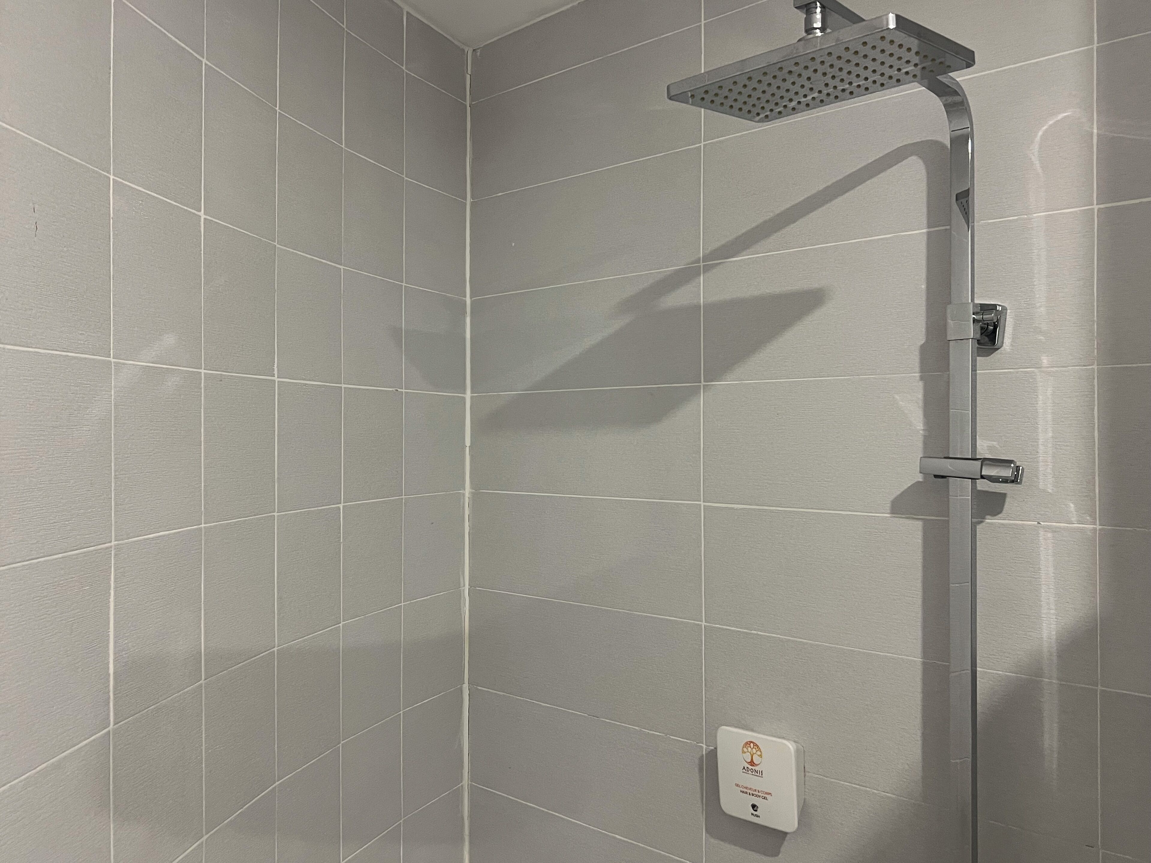 Chuveiro com chuveiro manual e painel de controle fixado na parede.